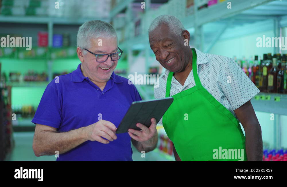 Senior manager showing tablet screen to older African American employee ...