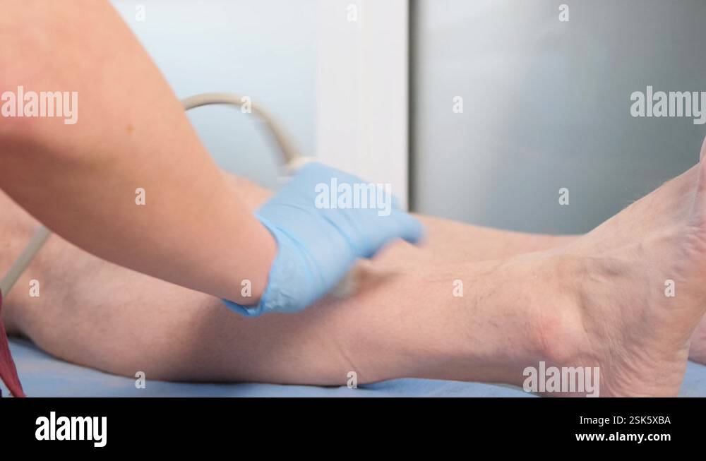 A female doctor uses sonography to take an x-ray of a patient's knee ...