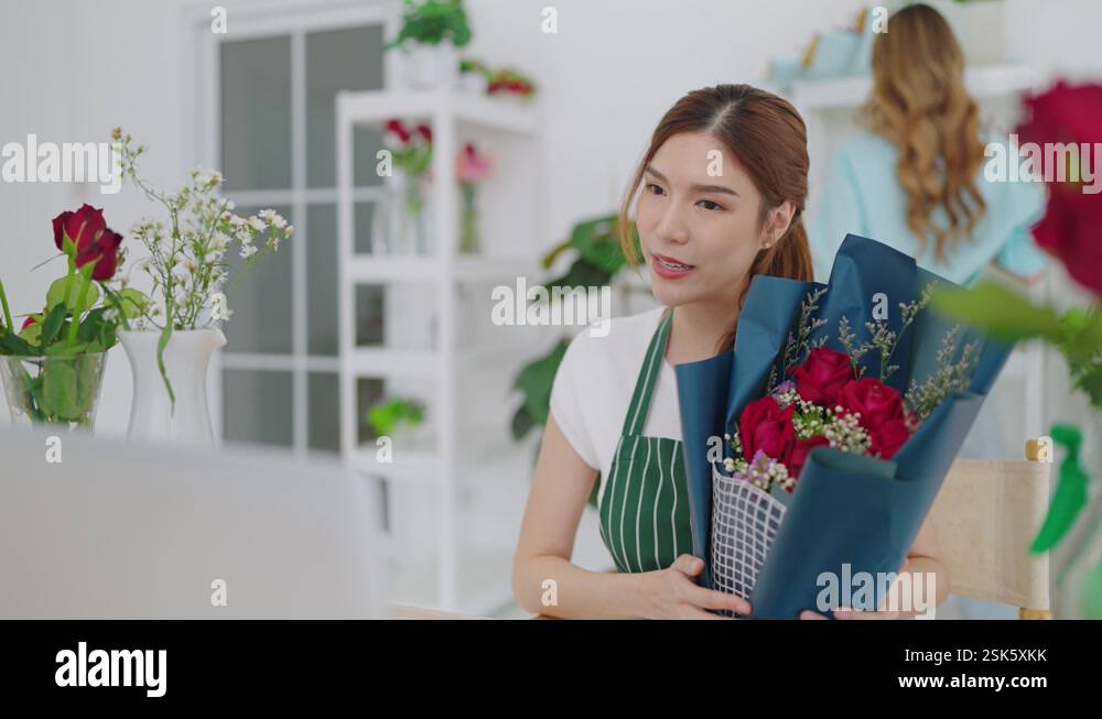 Women owner floral store holding bouquet while video call on laptop with client Stock Video ...