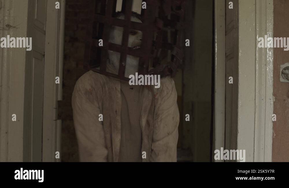 Ghost of maniac with cage on his head squirming in corridor of ...