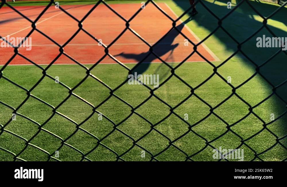 Shadow of a Tennis Player Playing on a Tennis court Behind a Fence ...
