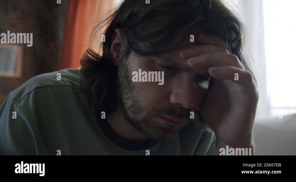 Man, overwhelmed, covers face in despair, depicting intense depression ...