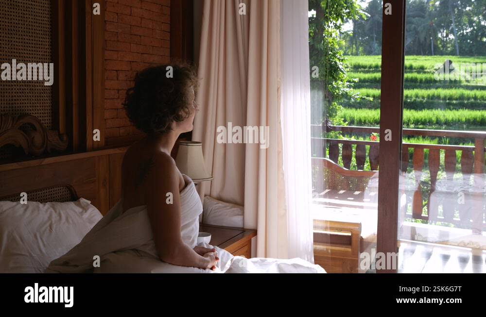 Close frame. The woman sits in silence and looks out the window wrapped ...