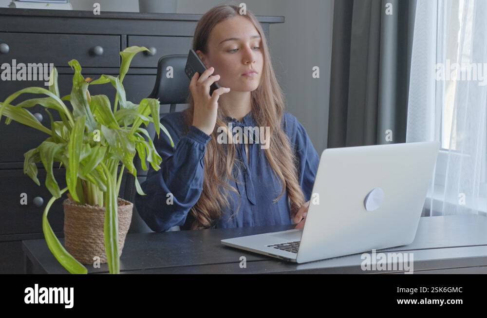 Young woman in a modern grey office picking up phone call, in Slow ...