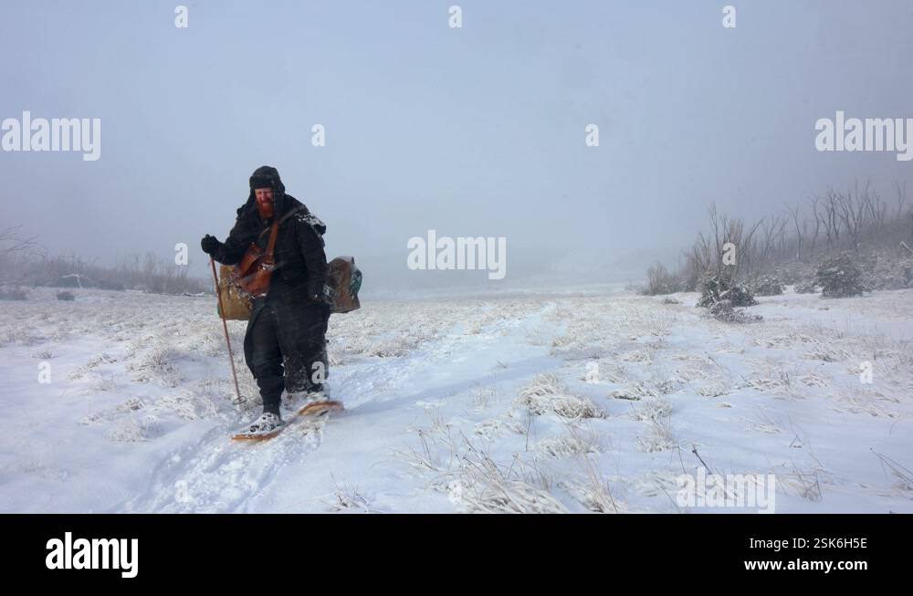 A man dressed as a polar explorer carries a swag in a snow storm ...
