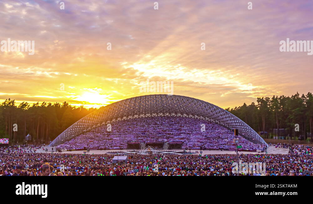 Oval shaped modern auditorium full of people with the golden sun at ...