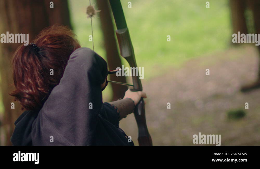 archery woman pulls and shoots arrow super slow motion back medium shot ...