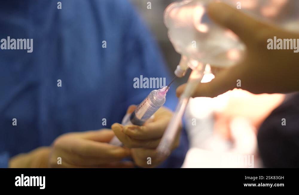 doctor with saline bag and syringe in operating room, operating room ...