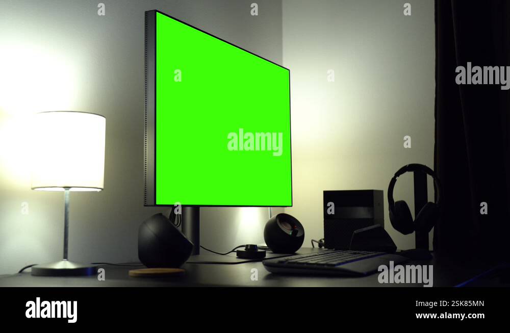 A desktop computer setup with a green screen on an office table ...