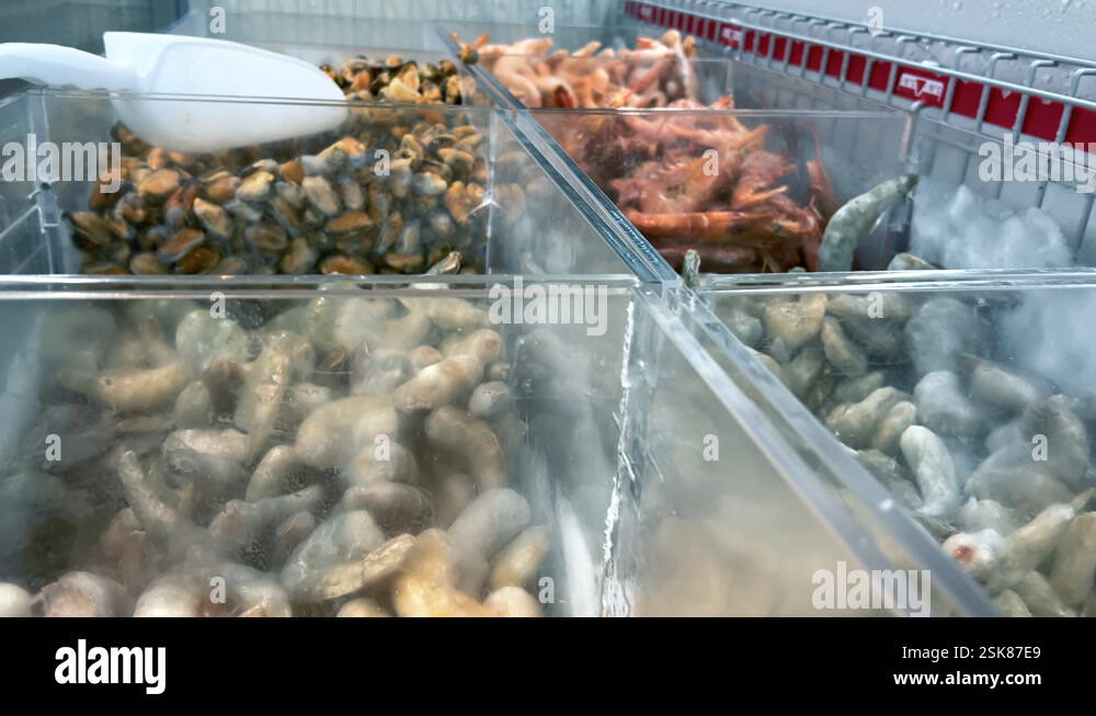 Frozen King prawns or royal shrimps and mussels in a display fridge in ...