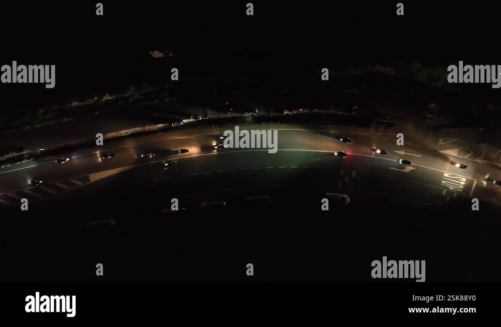Huge pack of bikers riding at night on a narrow road at night, aerial ...