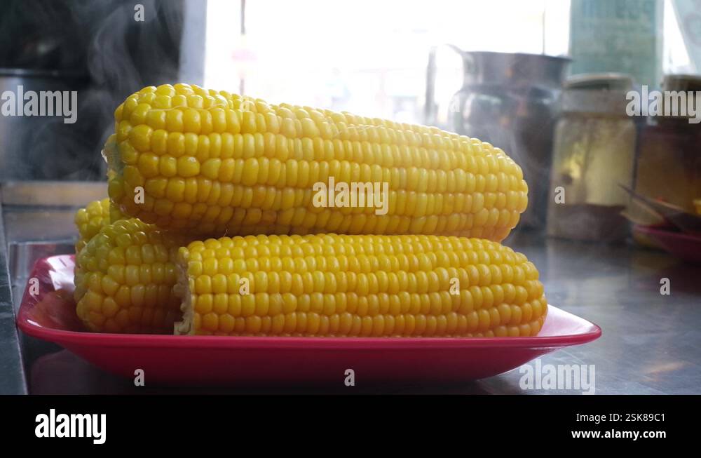 Close-up scene of steaming hot sweet corn filled in a dish with hot ...