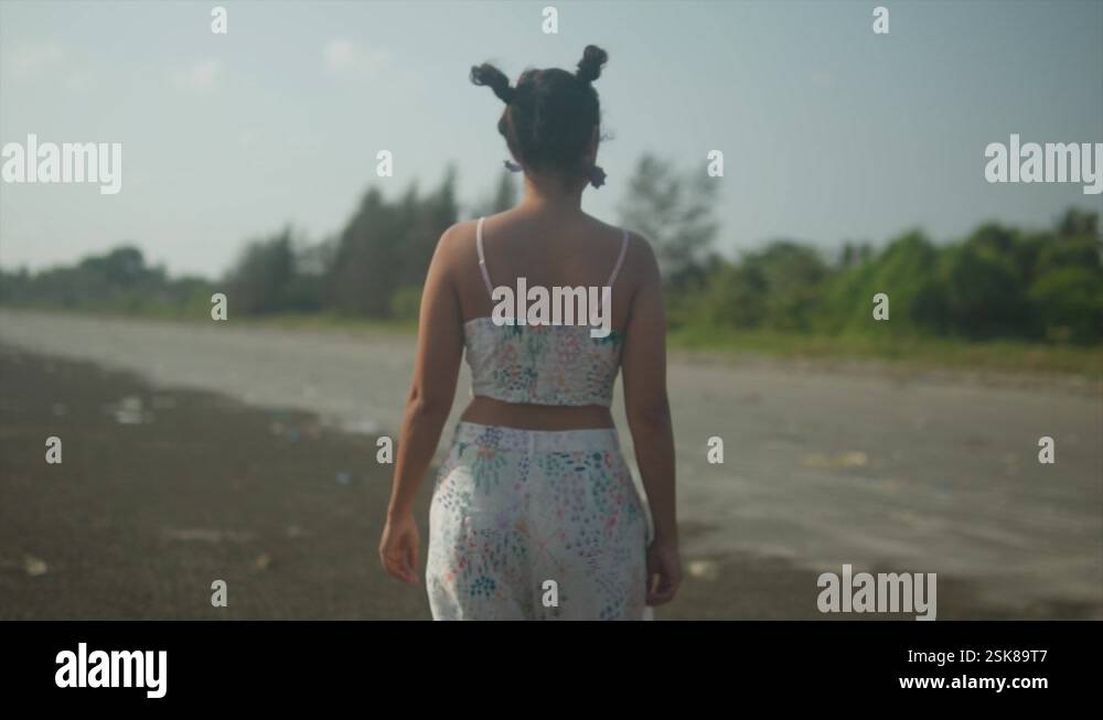 An Indian woman dressed in pristine white attire, seen from the back ...