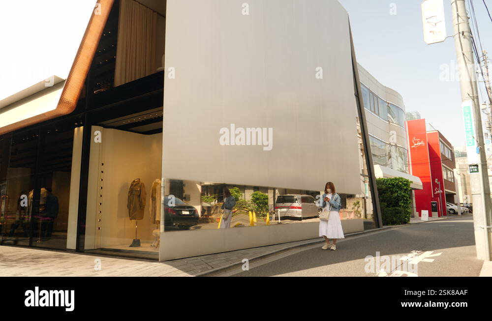 Girl walking past fashion store in posh shopping area. Tokyo, Japan ...