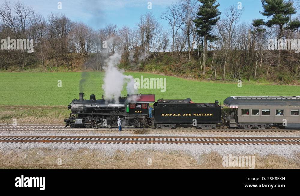 A Drone Slow Motion View of a Steam Passenger Train, Stopped, Engineer ...