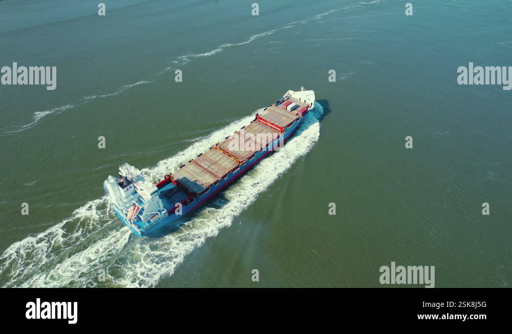 Aerial view of a cargo ship swimming through water living white foam in ...