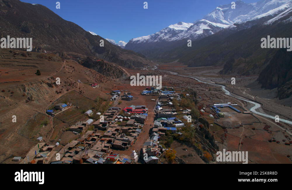 Aerial backwards view Manang village house rooftops with Himalayas ...