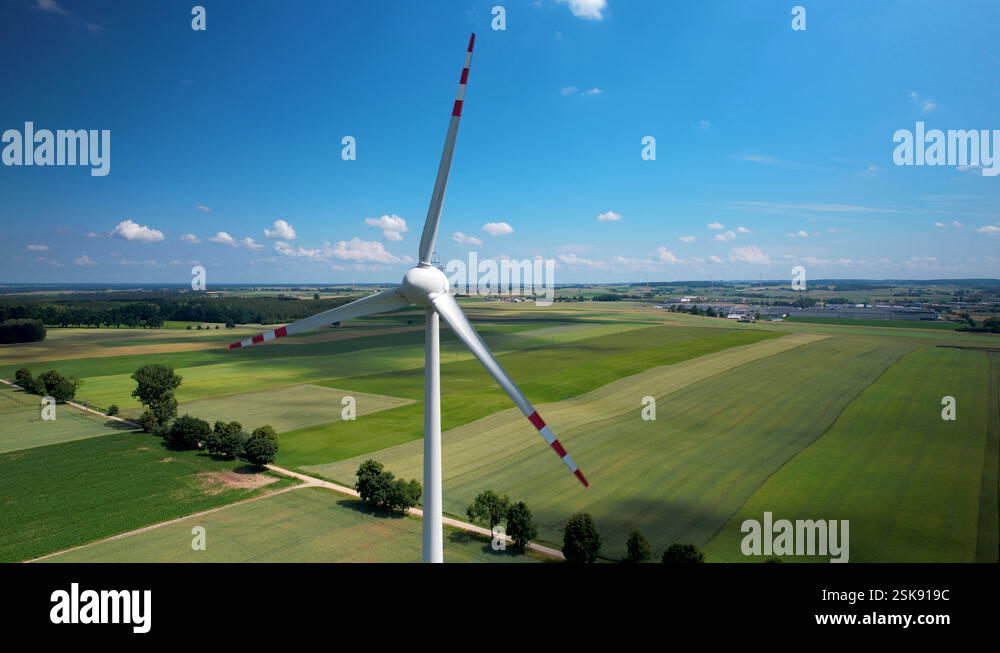 Drone pulls back from red white windmill turbine spinning above Stock ...