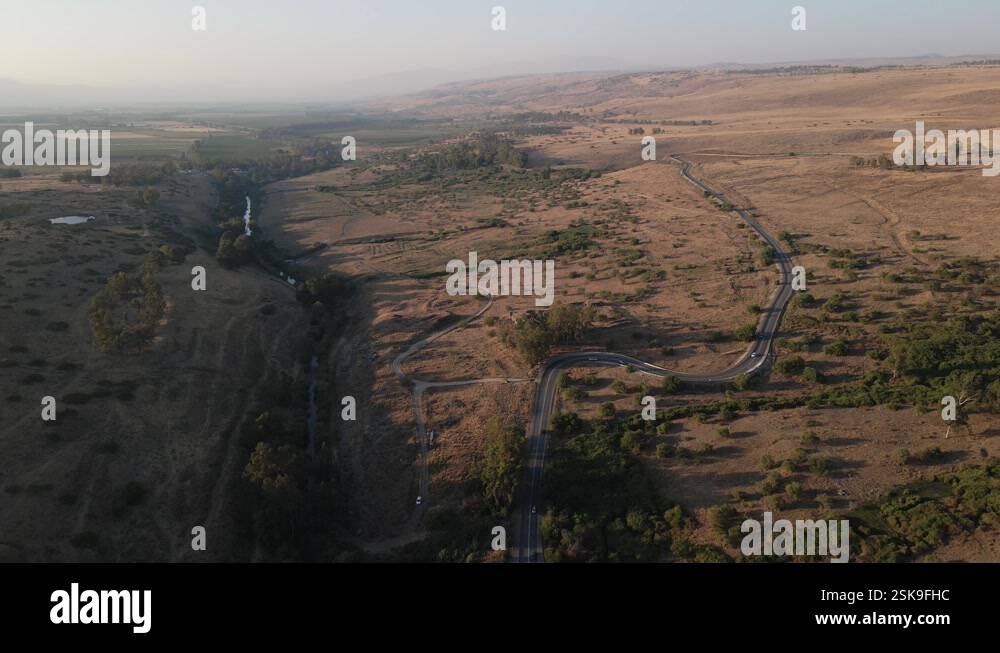 Curved road cutting through countryside next to Jordan River, Israel ...