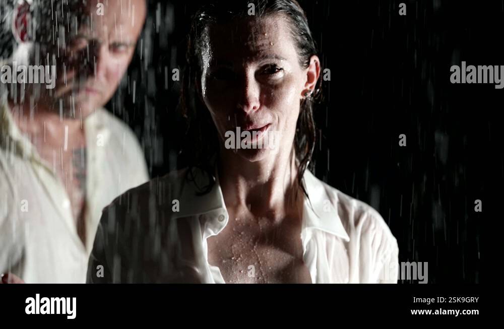 Portrait of a pretty adult woman standing wet in the rain at night in ...