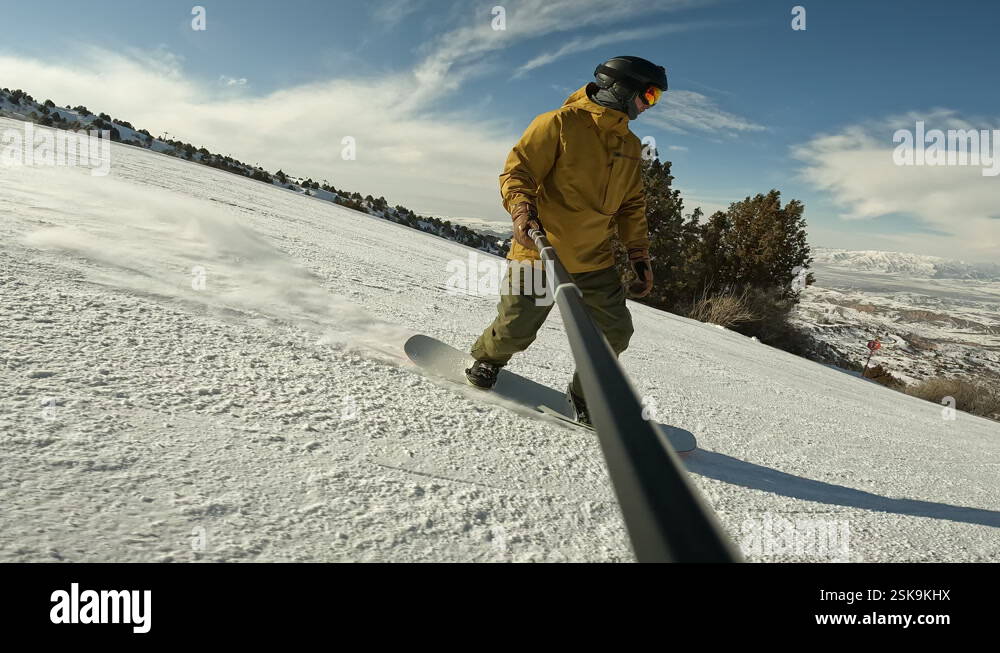 Person on snowboard with selfie stick rides on prepared snow track ...