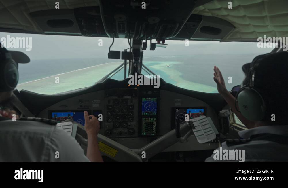Seaplane pilots navigating above tropical island atoll, cockpit view ...
