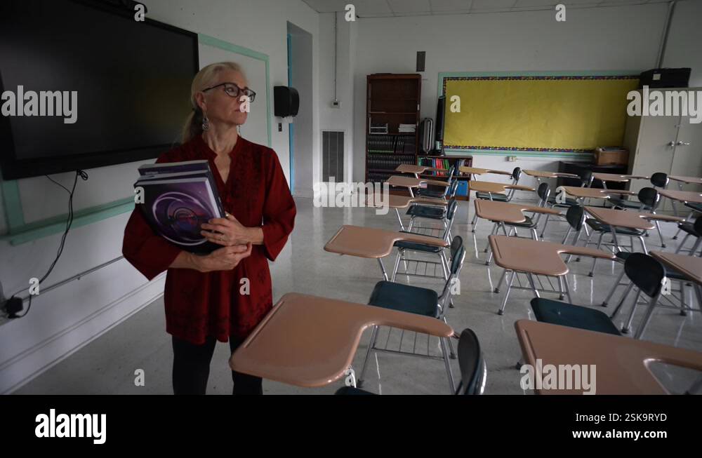 Wide angle push in view of sad teacher in an empty classroom with the ...
