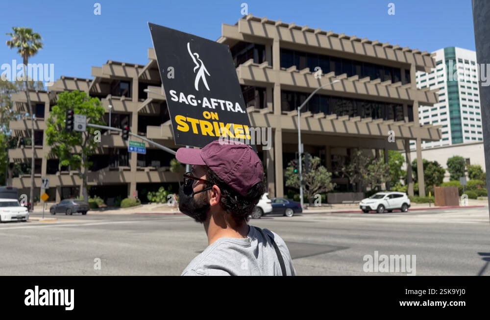 A SAG-AFTRA striker pumping fist and holding picket sign outside Warner ...