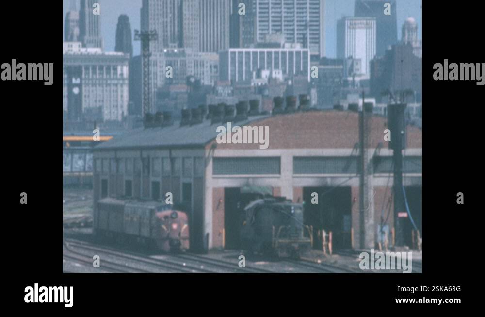 1960s: Commuter train travels on elevated train tracks into city, past ...