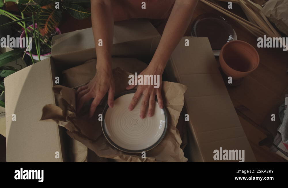 Prepare for a move. Woman wrapping ceramic plates in brown paper Stock ...