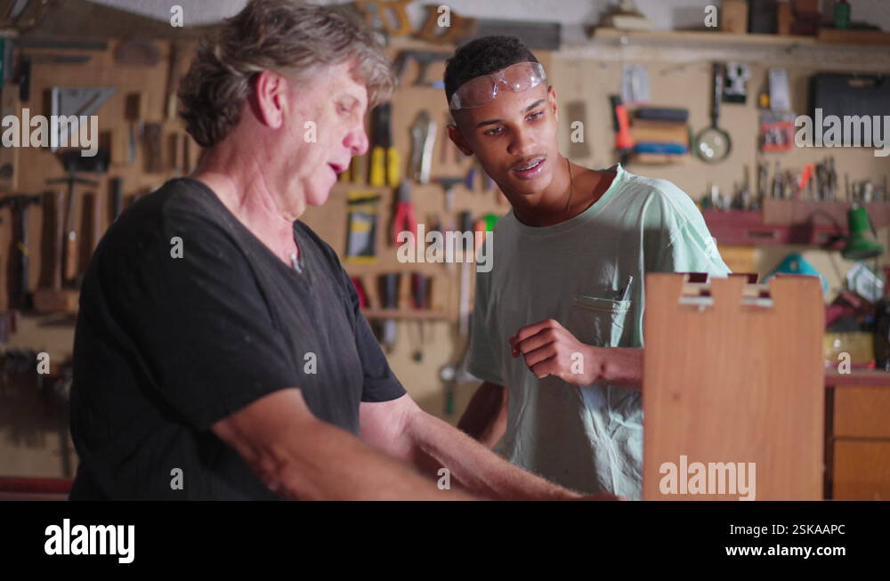 Senior carpenter guiding young apprentice to build craftsmanship ...