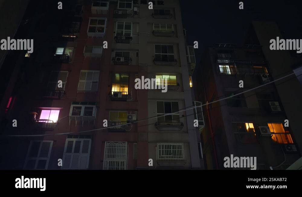 Warm and cool light comes out from apartment building windows at night ...