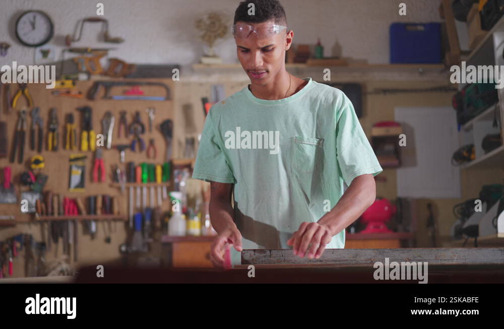 Young apprentice at carpenter workship sawing and measuring piece of ...