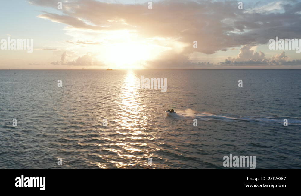 Aerial side tracking back lit jet-ski with couple of riders ride at ...