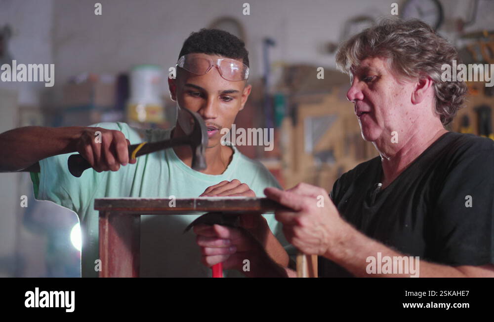 Master carpenter orienting young apprentice to do woodwork at carpentry ...
