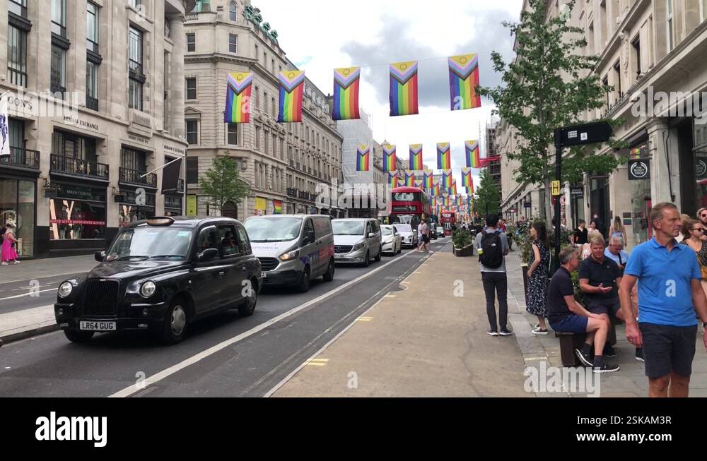 People walk under some LGBTQ flags that fly along Oxford Street, London ...