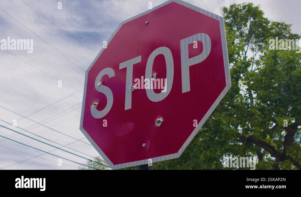 stop sign riddled with bullet holes, welcome to our town, stop violence ...