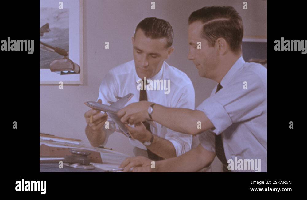 1960s: Men working at drafting table, man picks up model airplane Stock ...