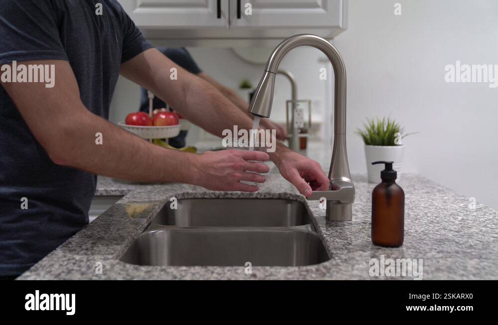 Filling up clear glass with fresh clean drinking water from tap faucet ...