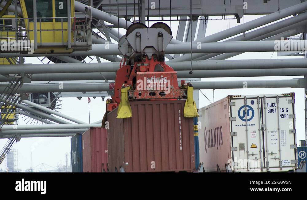 Close-up cargo crane lifts a red ship container, loading vessel at ...