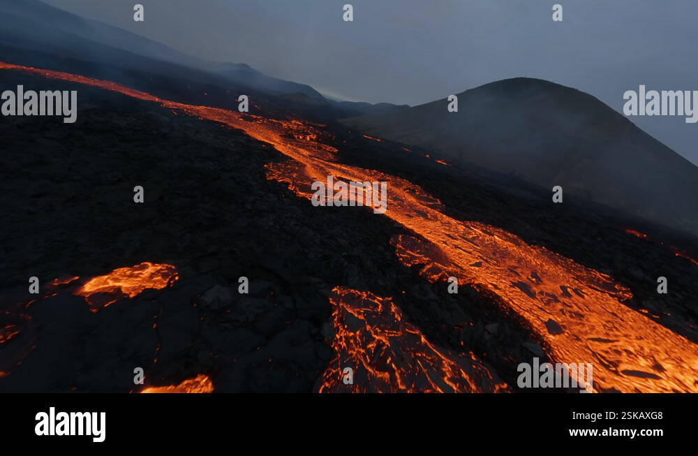 FPV drone shot diving over a glowing magma river and volcanic rock at a ...