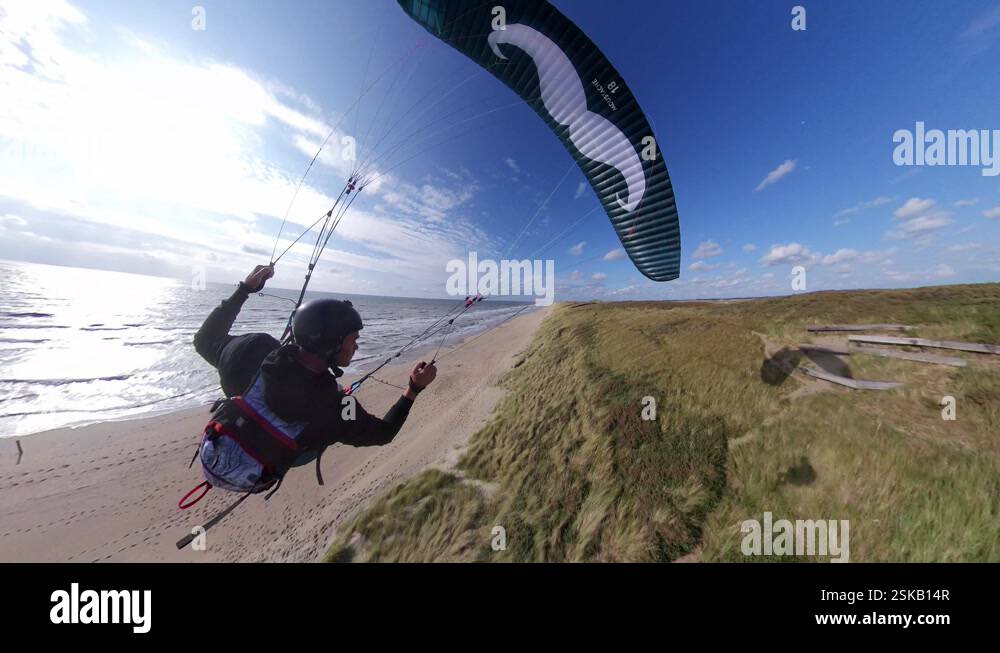 Speed soaring with paraglider along coastline over dunes ...