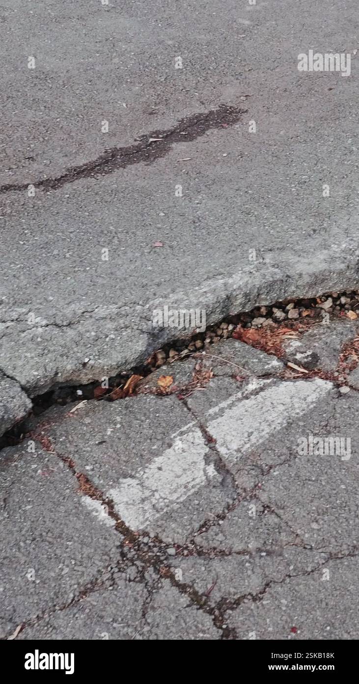 Crack with deep faults on the road next to the white road markings ...