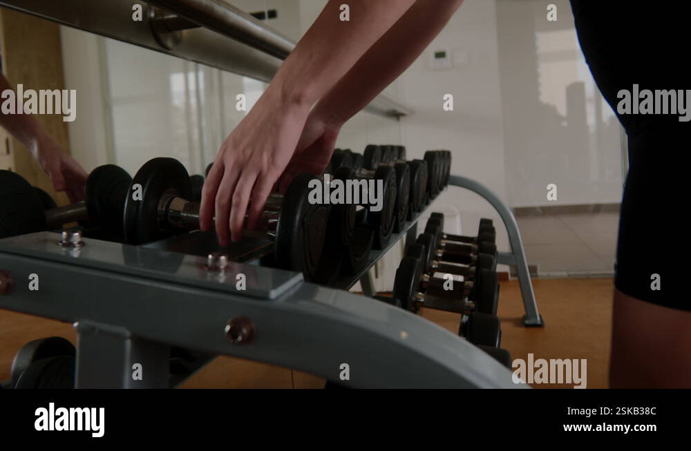 Female hands taking bodybuilding dumbbells in gym club. Close up woman ...