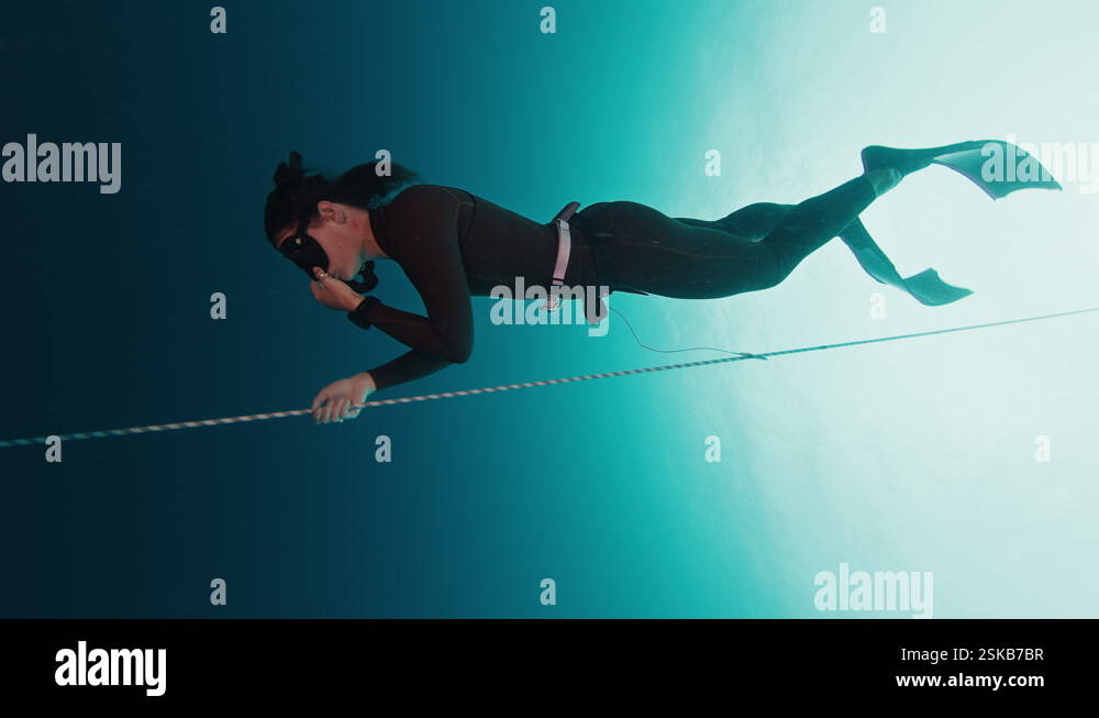 Freediver works out on rope. Woman free diver trains along the rope in ...