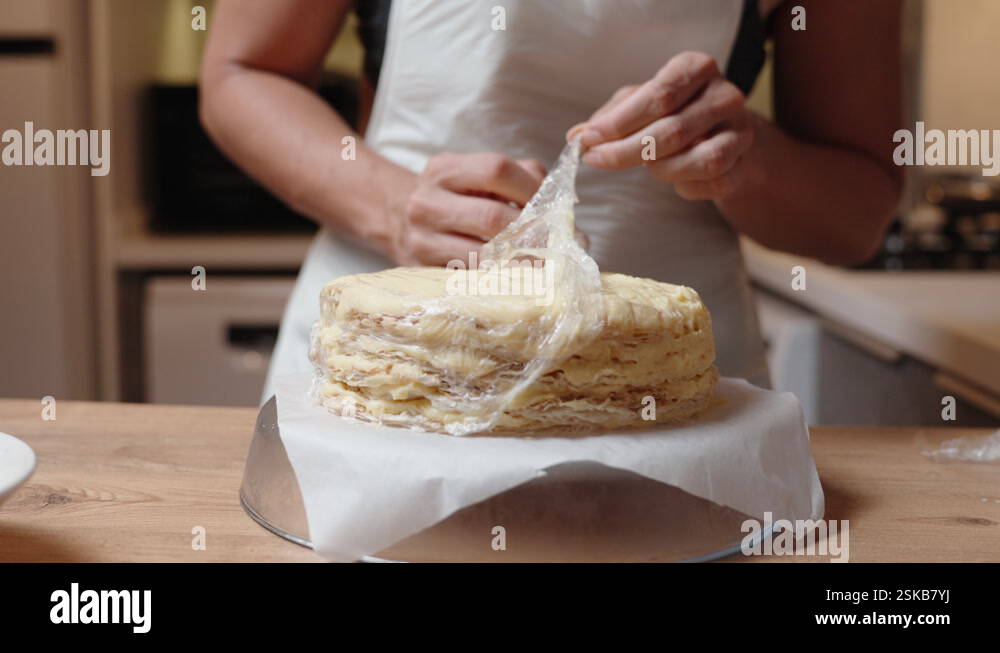 The pastry chef removes the plastic wrap from the Napoleon cake base ...