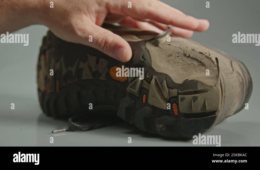 hand grabbing worn hiking shoes with torn heel on the sole Stock Video ...