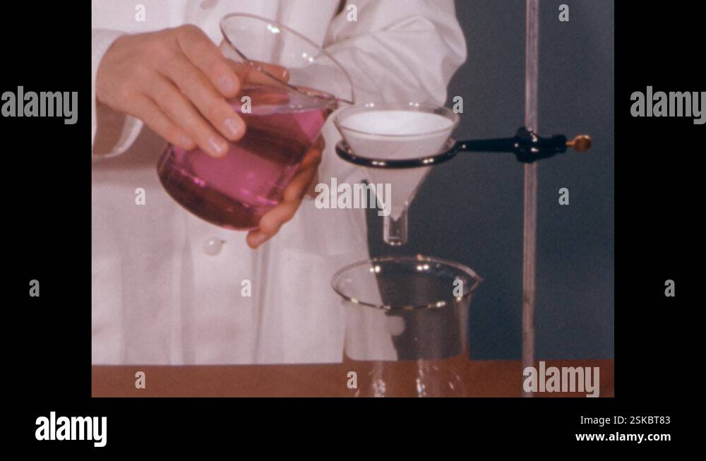 1960s: Scientist pours beaker of pink liquid through funnel into other ...