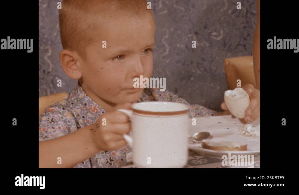 1960s: Kitchen. Little boy eats egg and toast. Boy sips from mug Stock ...