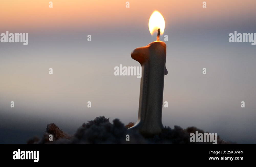 Burning candle shape number 1 One sand beach sea shore water waves ...